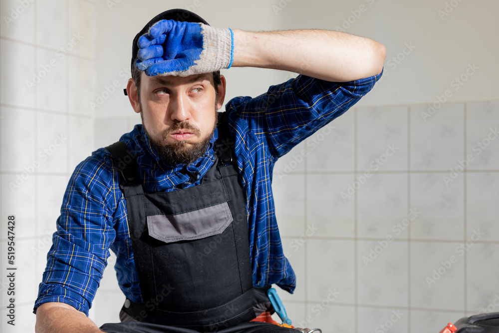 Close-up portrait of face of exhausted tired man in work overalls and ...