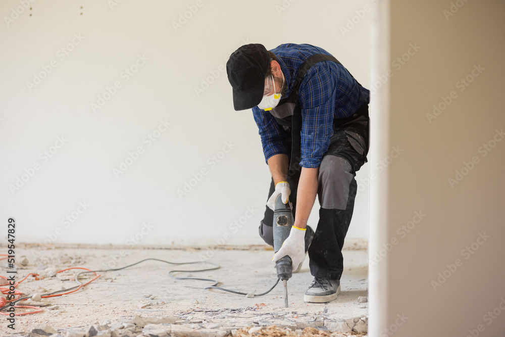 View of a construction worker using a hand-held demolition hammer and ...