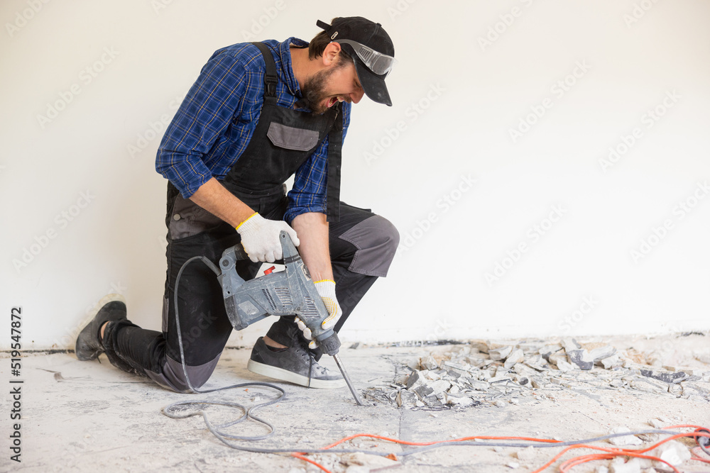View of a construction worker using a hand-held demolition hammer and ...