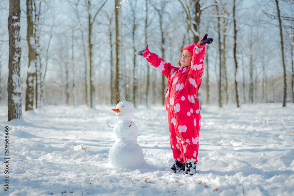Little girl building snowman in snowy park. Active outdoors leisure ...