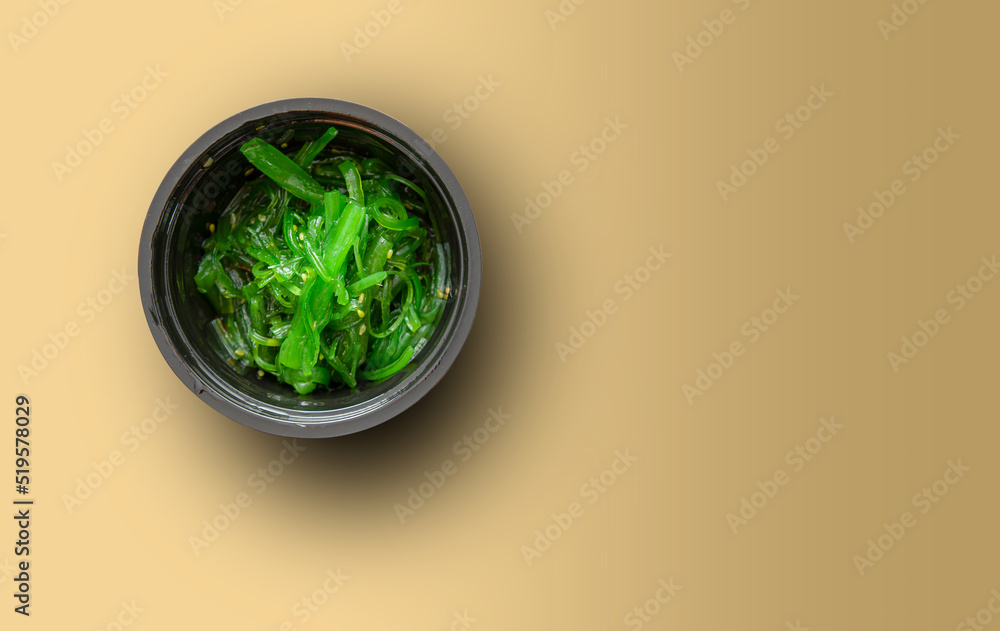 Japanese seaweed salad or wakame seaweed in a cup on a yellow ...