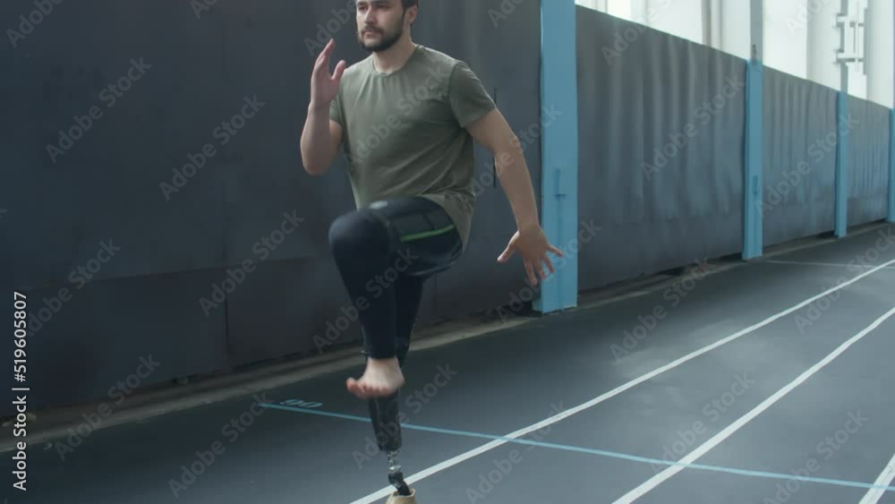 Male athlete with prosthetic leg doing high knee walk while exercising ...