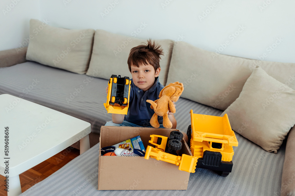 Caucasian little boy, packing toys and clothes into cardboard box for ...