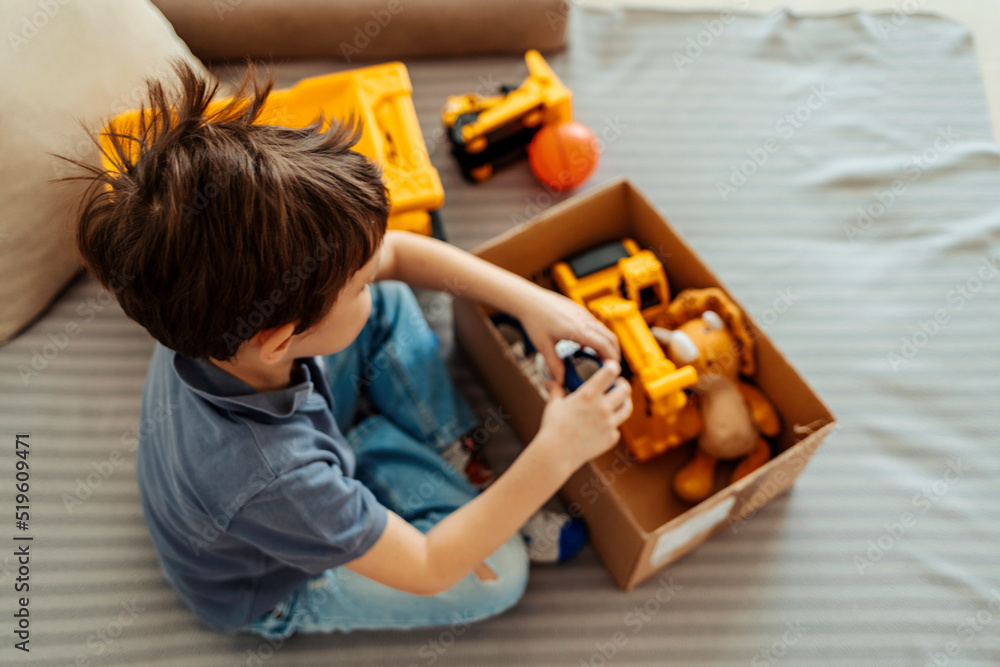 A boy holding a box for donations of toys and clothes. Old toys in box ...