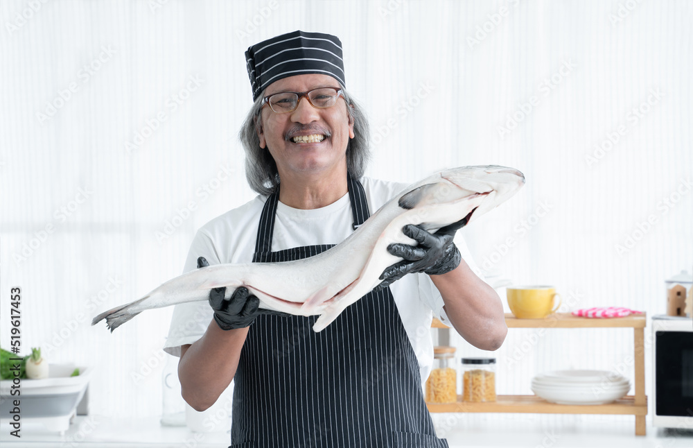 Portrait of happy Asian senior man chef is holding and showing fresh ...