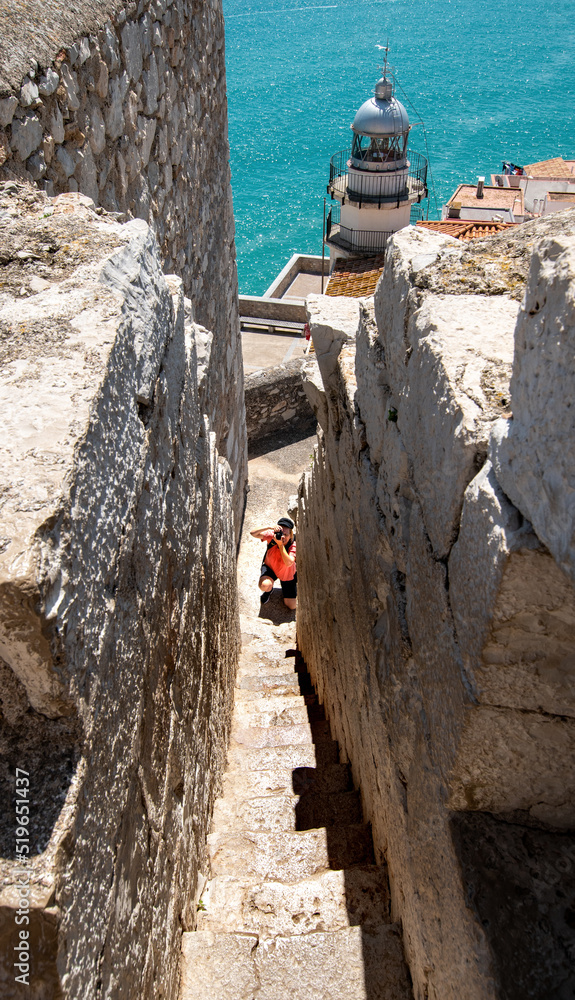 Female photojournalist takes a picture whilst looking up a long narrow ...