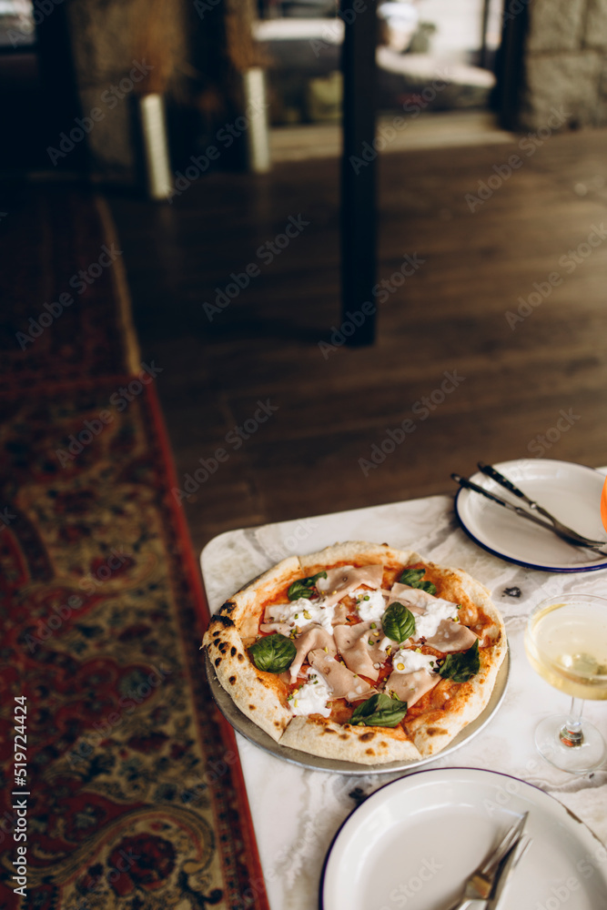ready hot pizza on a marble table with a glass of sparkling wine in a ...