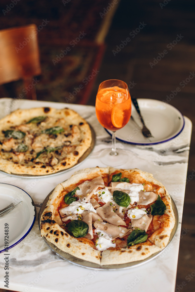table setting in a pizzeria. two Italian pizzas with burnt sides and a ...