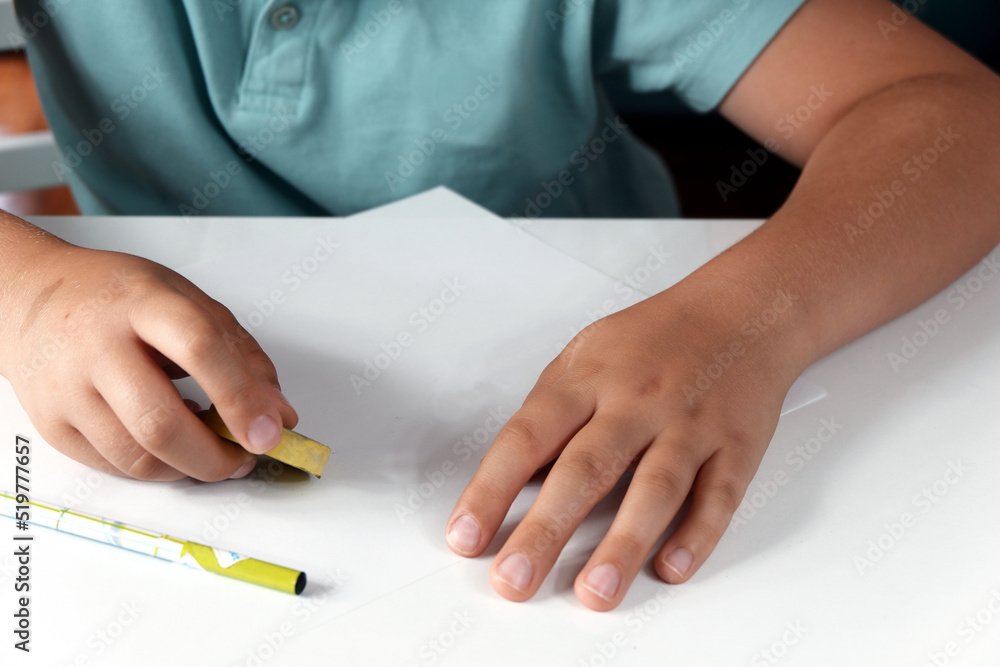 Back to school. The child erases the text on the white paper with an ...