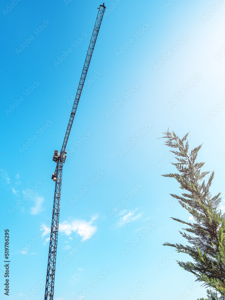 Tower crane against the sky. Bottom view of a long crane towering over ...
