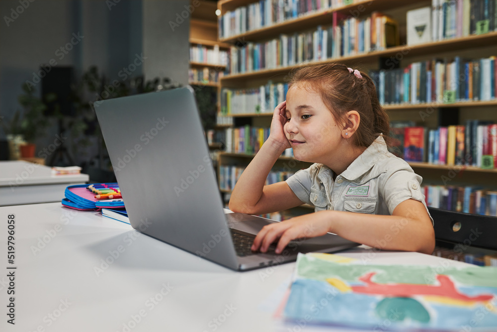 Engaged student doing her homework using laptop in after school club at ...