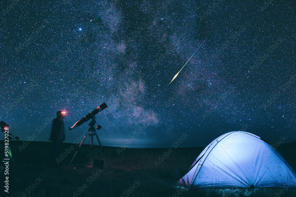 Amateur astronomer with astronomical telescope camping in nature under ...