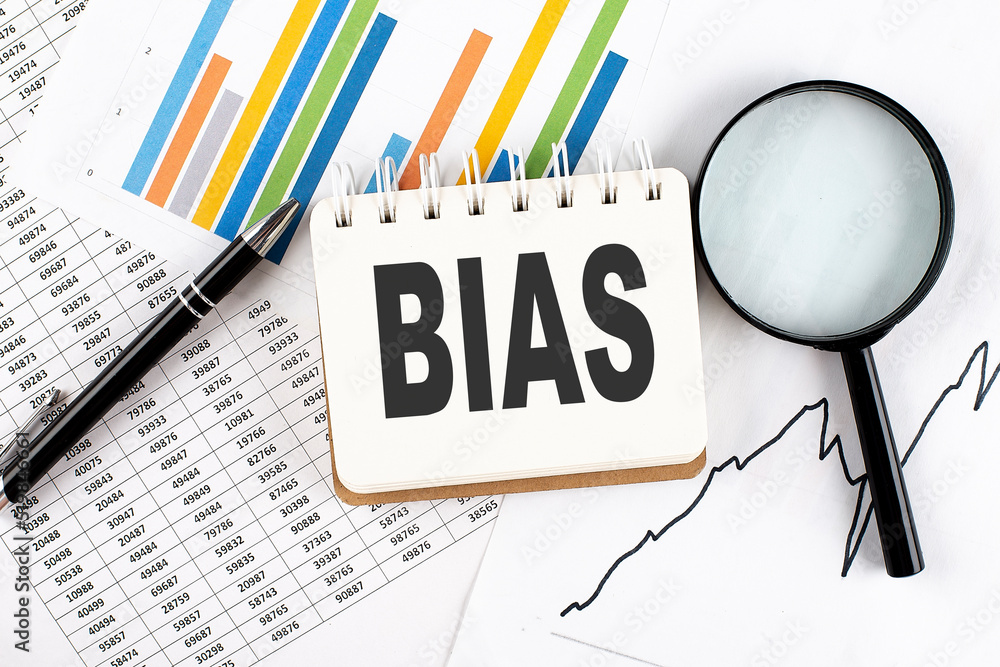 BIAS text on notebook on the graph background with pen and magnifier ...