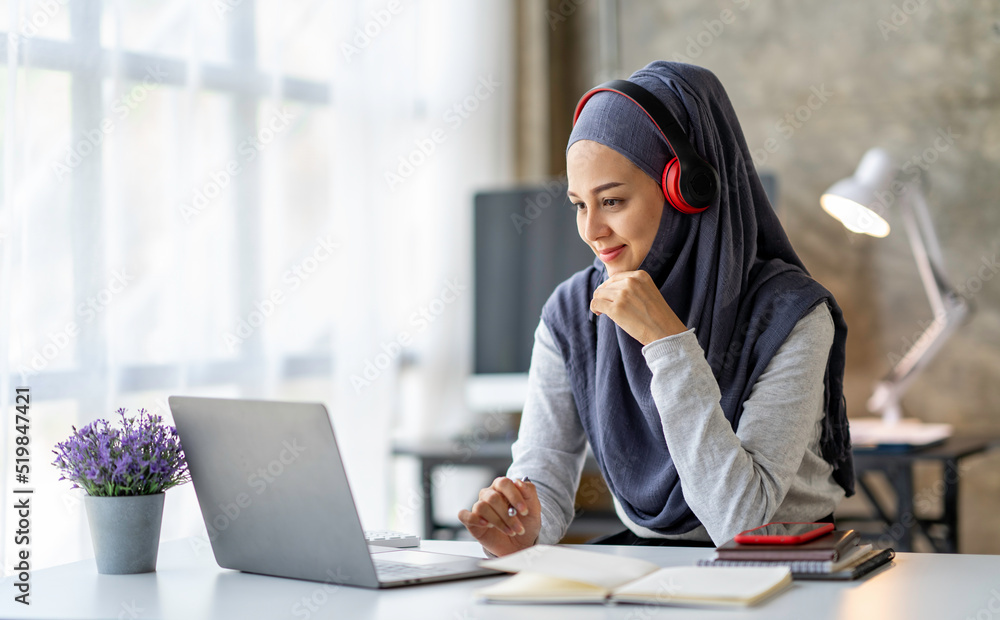 Muslim businesswoman wearing a hijab looks at camera working Online ...