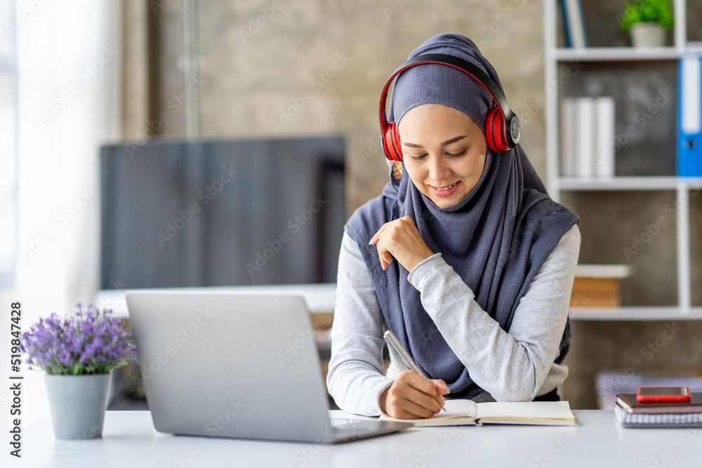 Muslim businesswoman wearing a hijab looks at camera working Online ...