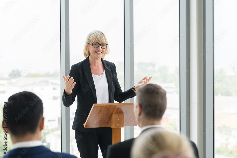 Senior business woman talking at podium speaker. Senior business woman ...