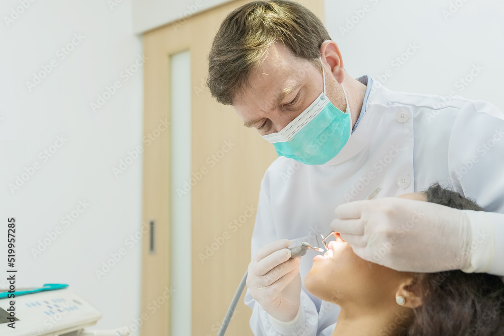 Asian female dentist examining young girl patient's teeth at dental ...