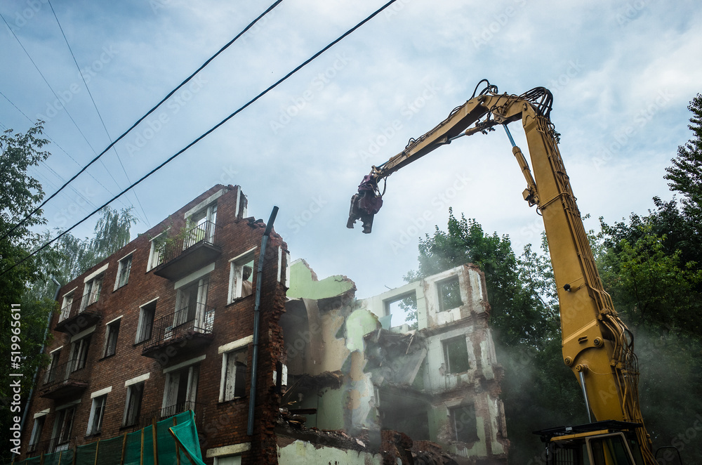 Demolition of a brick building with excavator mechanical arm ...