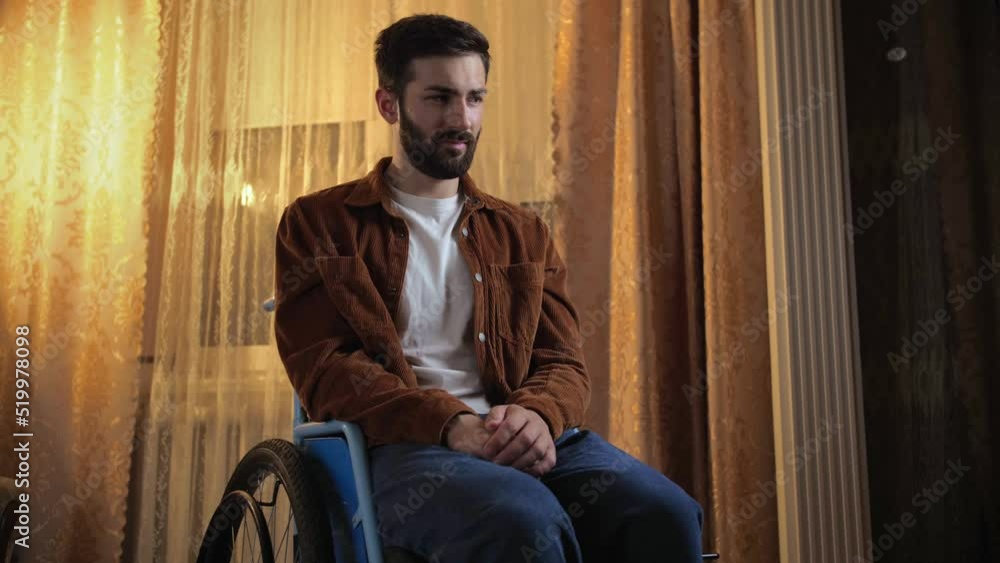 Sad Young man in a wheelchair sits with sadness showing on his face. An ...