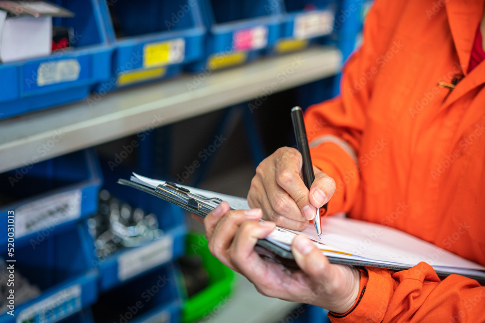 A storekeeper is performing inventory checklist with background of ...