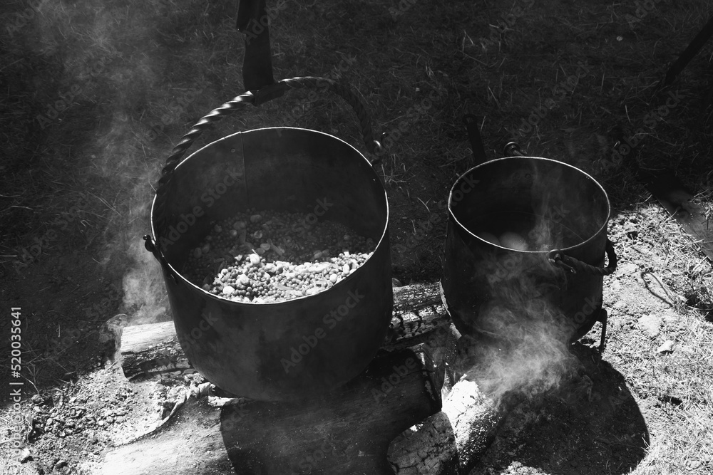 Medieval meal (peasant green pea stew, eggs) is prepared in cauldron on ...