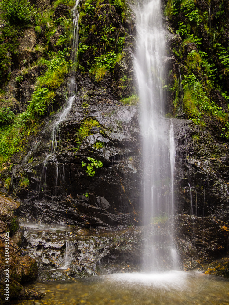 Detalle de una cascada de un rio de montaña que cae entre rocas y ...