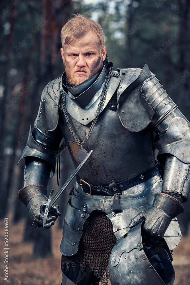 Knight covered in blood with a sword on the battlefield. Man in armor ...