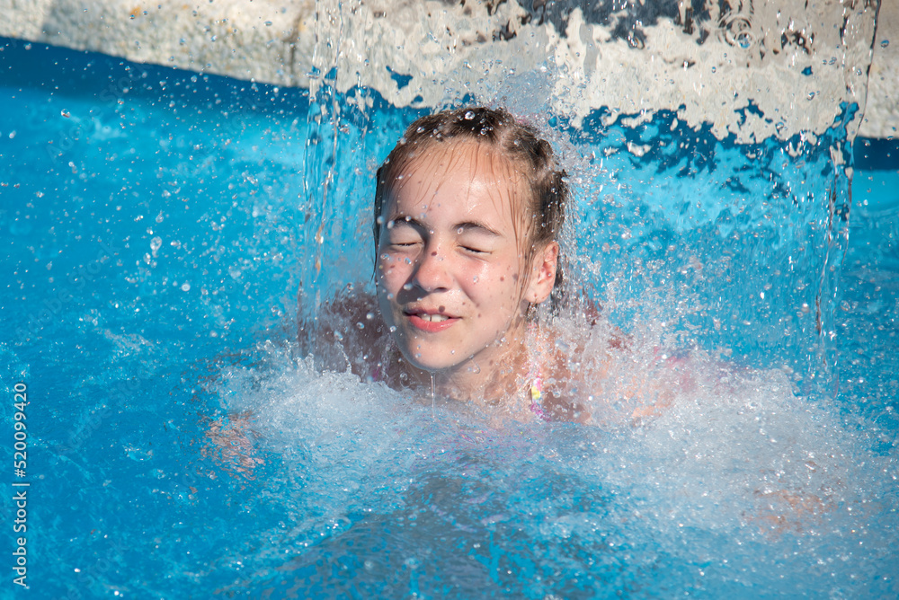 A teenage girl of 11-13 years old swims in a pool with blue water. She ...