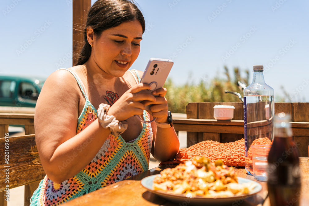 Chica joven guapa feliz en la playa tomando foto sy mirando el telefono ...