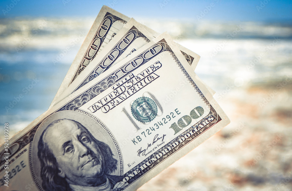 Girl holding money bill of 300 dollars on background of sea ocean waves ...