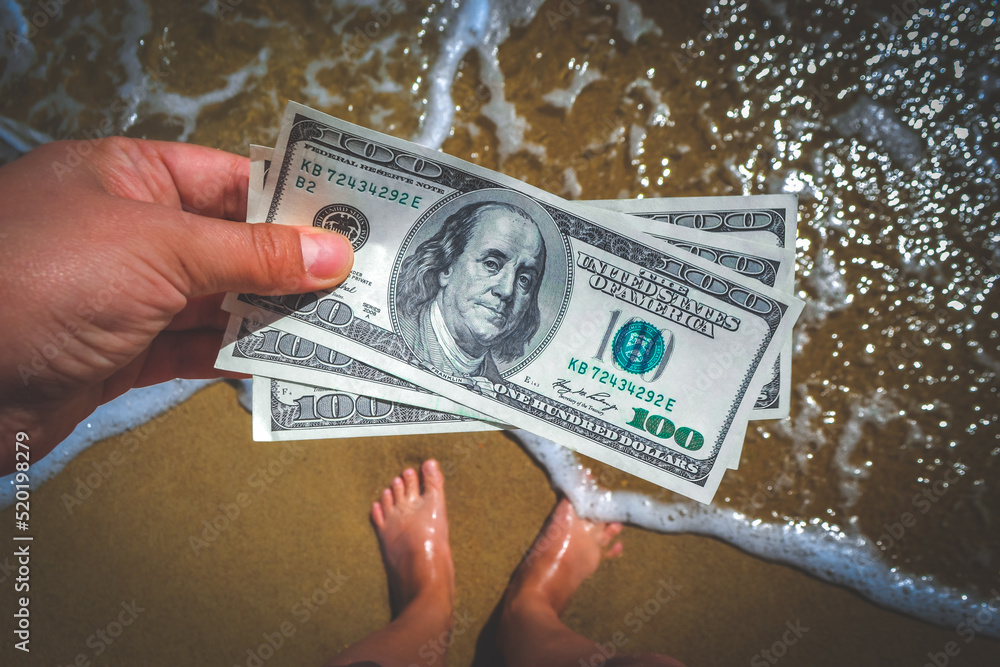 Girl holding money bill of 300 dollars on background of sea ocean waves ...