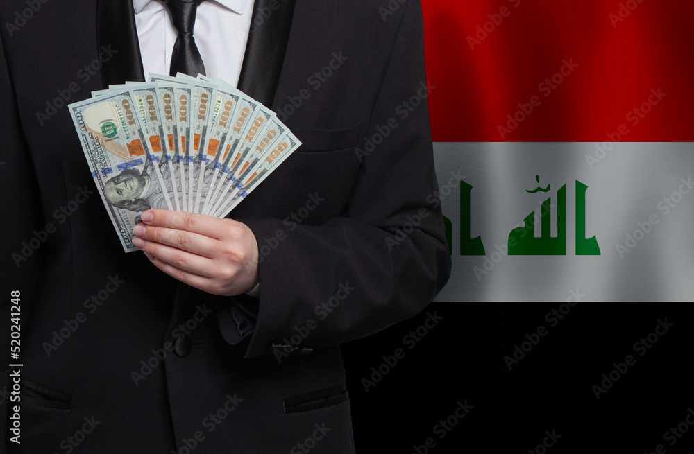 Iraqi business man hand showing US 100 dollar bills against flag of ...