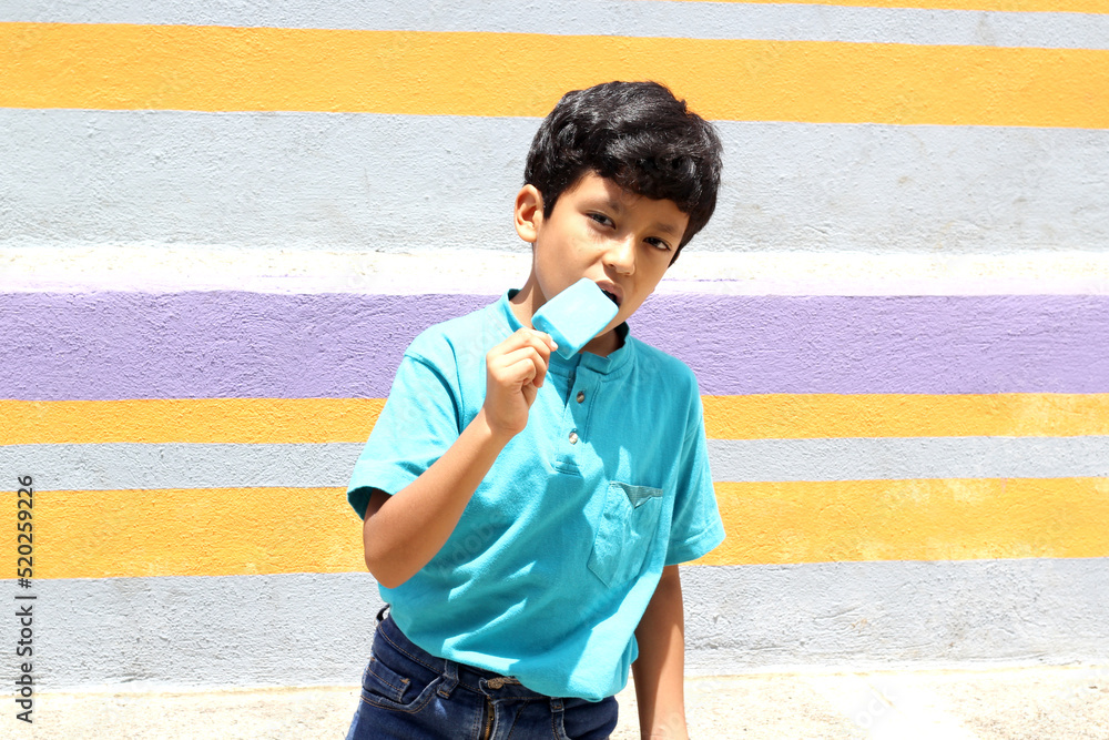 Poor Latino dark-haired boy with a blue t-shirt sitting on a park bench ...