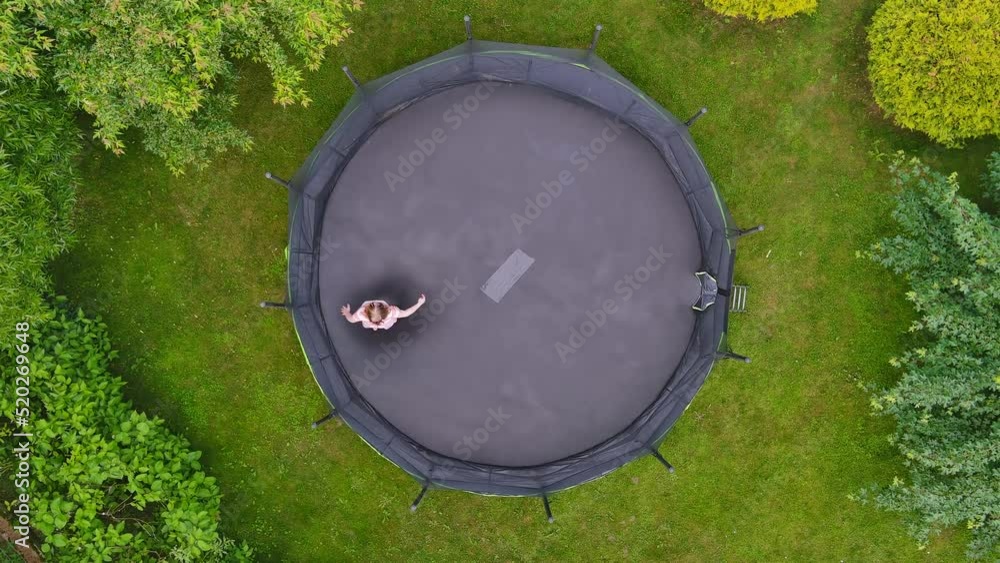 Aerial top-down view of a teenage girl jumping on trampoline in a ...