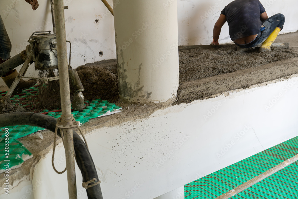 Construction worker uses trowel to level cement mortar screed. Concrete ...