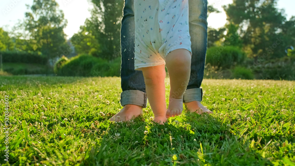 Foto de Child learns to take the first steps on the grass. Baby learns ...