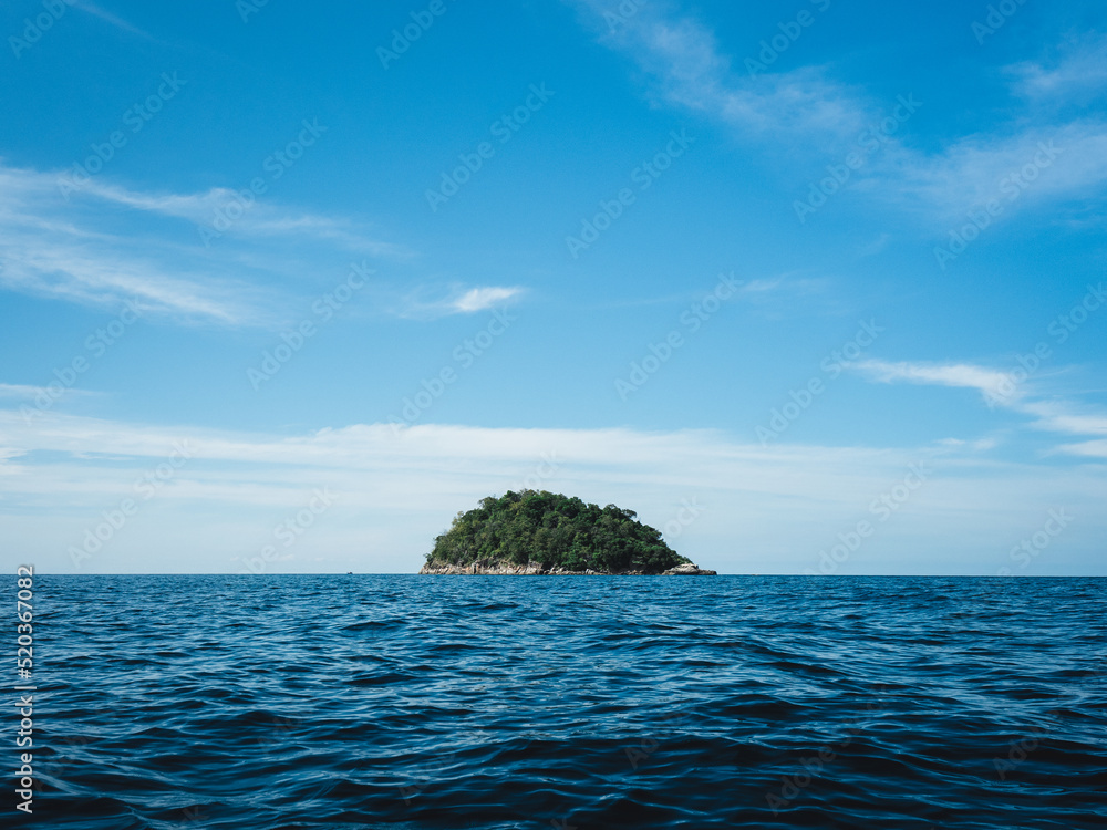 Scenic view of small lonely isolated island in the middle of blue sea ...