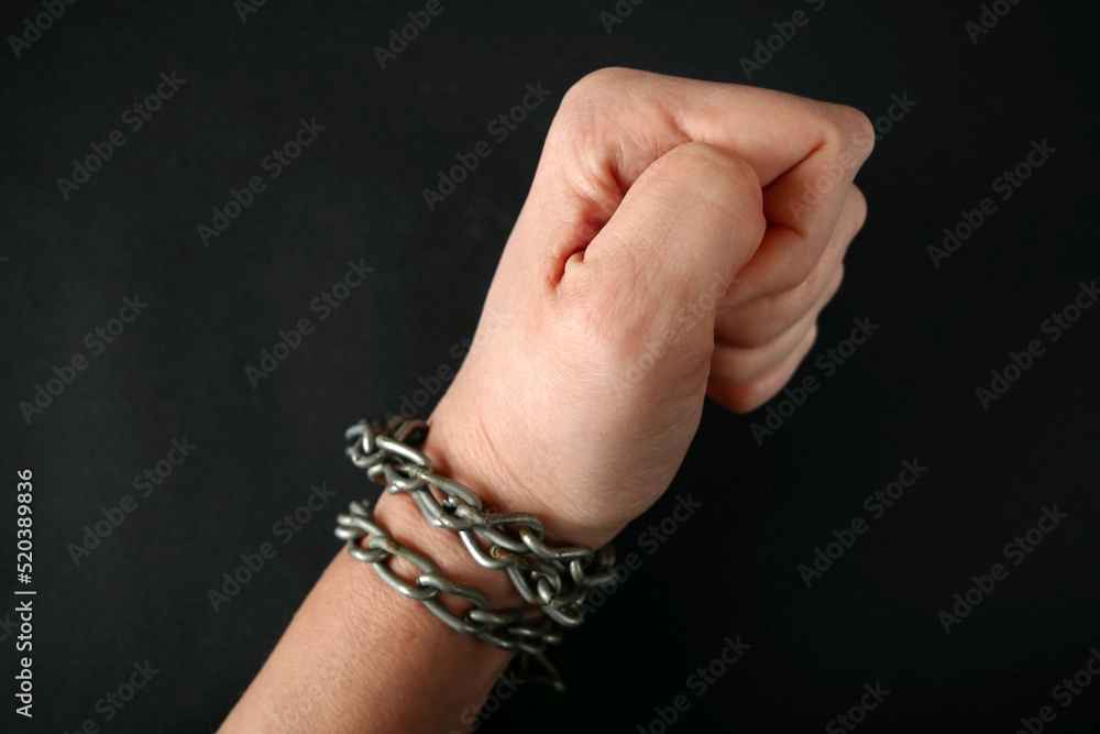 hands clenched into fists in handcuffs in the form of chains on a black ...