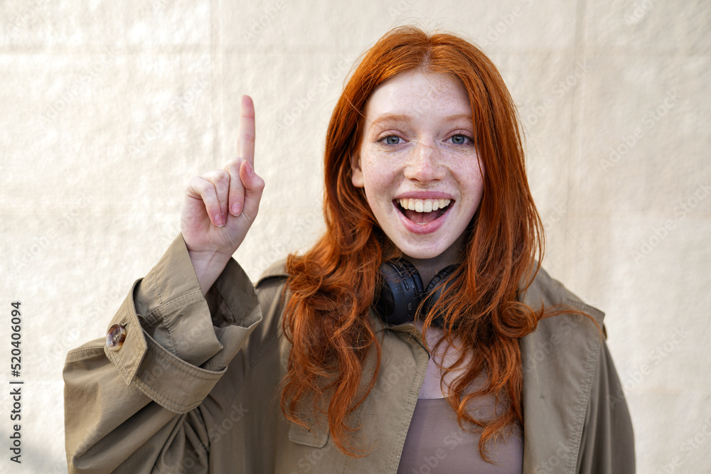 Happy teen redhead fashion girl standing on urban wall background ...