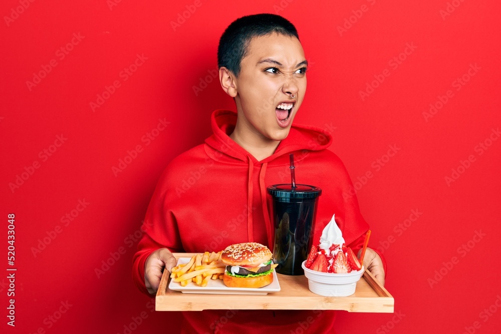 Beautiful hispanic woman with short hair eating a tasty classic burger ...