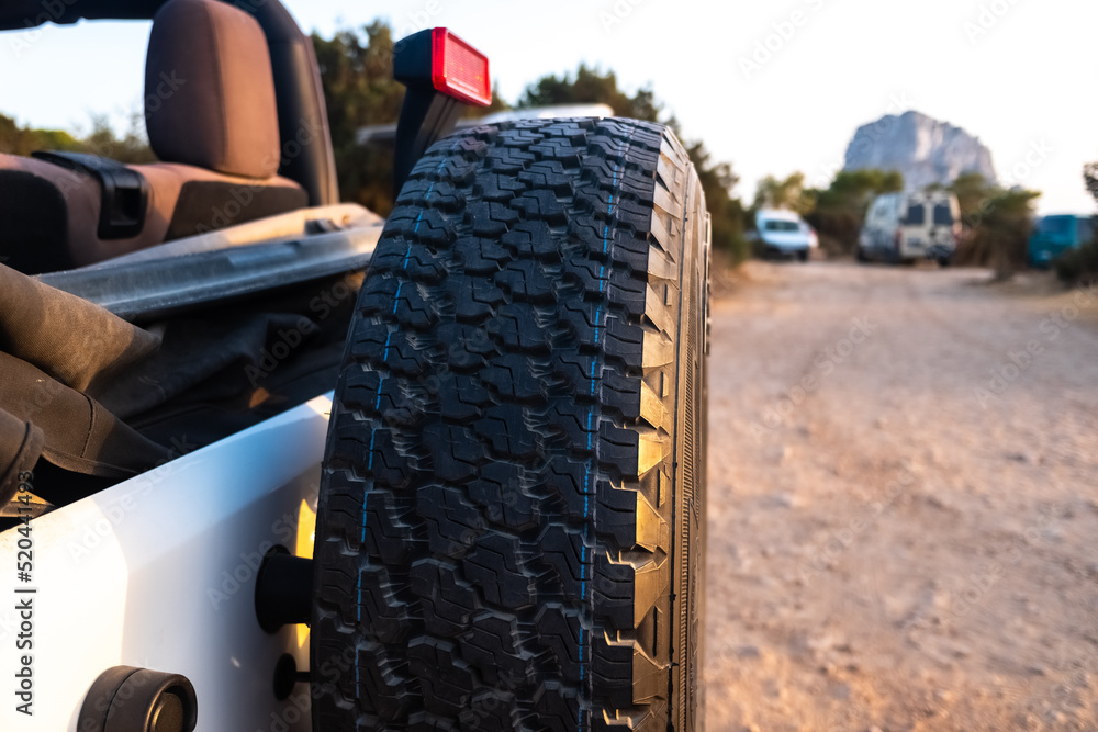 Spare wheel of an off-road car, placed in the back during an excursion ...