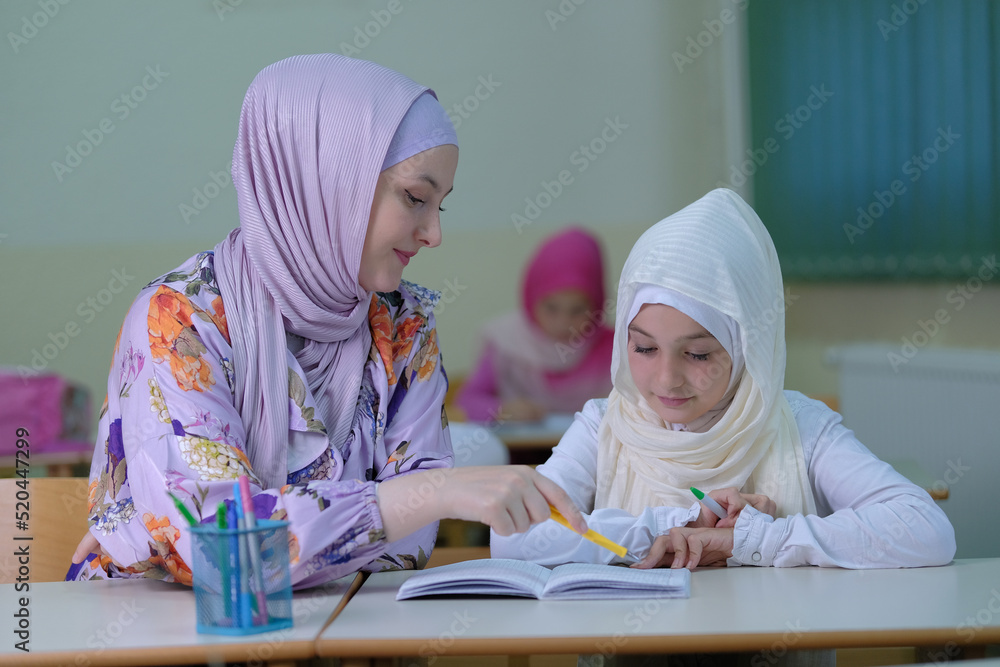 Female hijab Muslim teacher helps school child to finish the lesson in ...