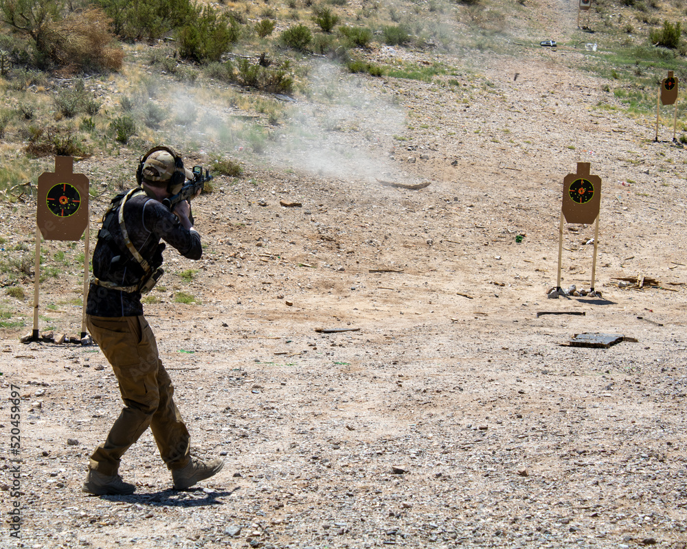 Person wearing military gear shooting ar15 pistol while walking and ...