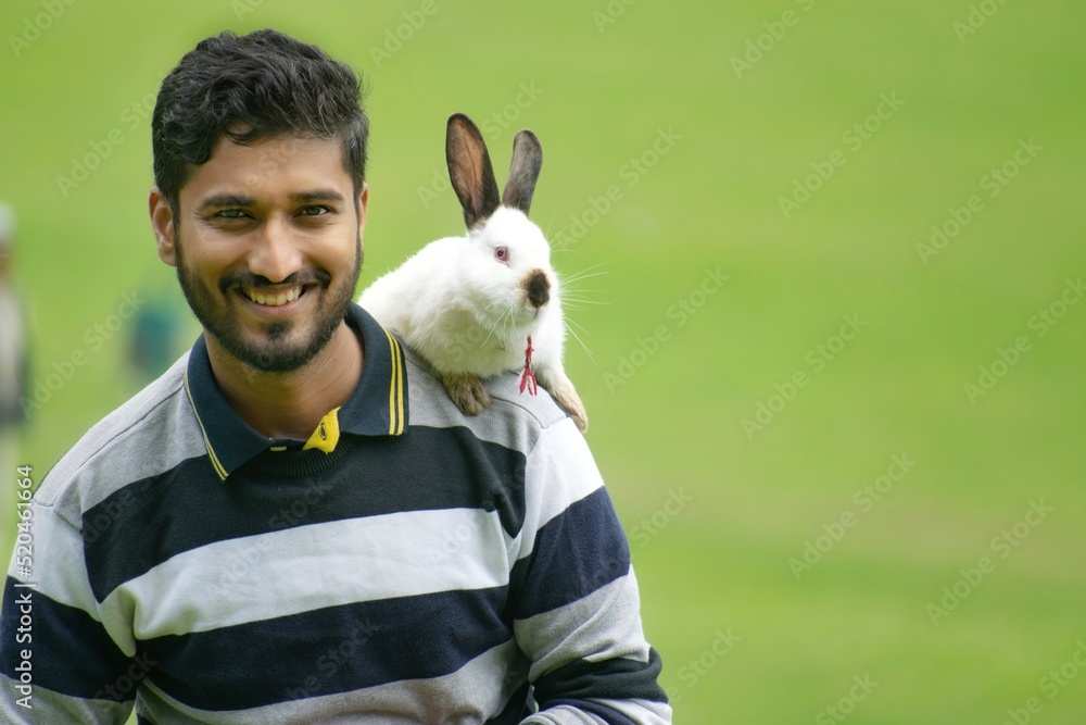 A handsome Indian Asian man, boy, male along with rabbit on shoulder ...