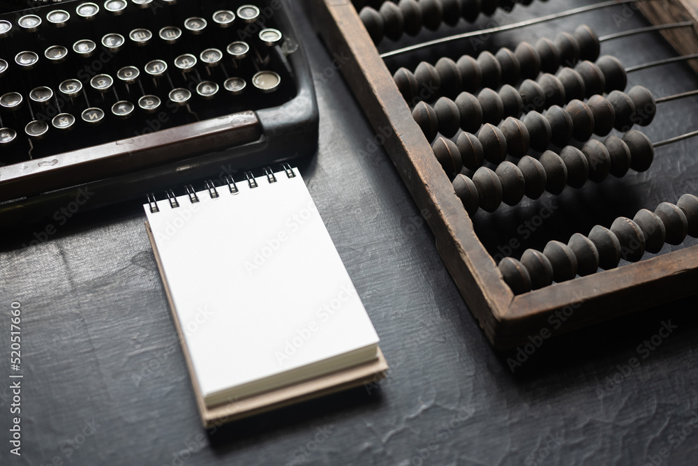 Blank page notepad with copy space, typewriter and abacus on the black ...