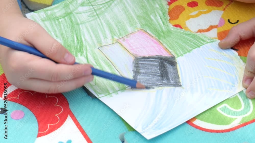 School age child drawing a picture using a pencil crayon, hands detail ...