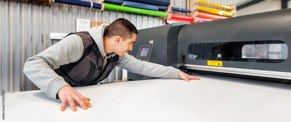 Technician operator works on large premium industrial printer plotter ...