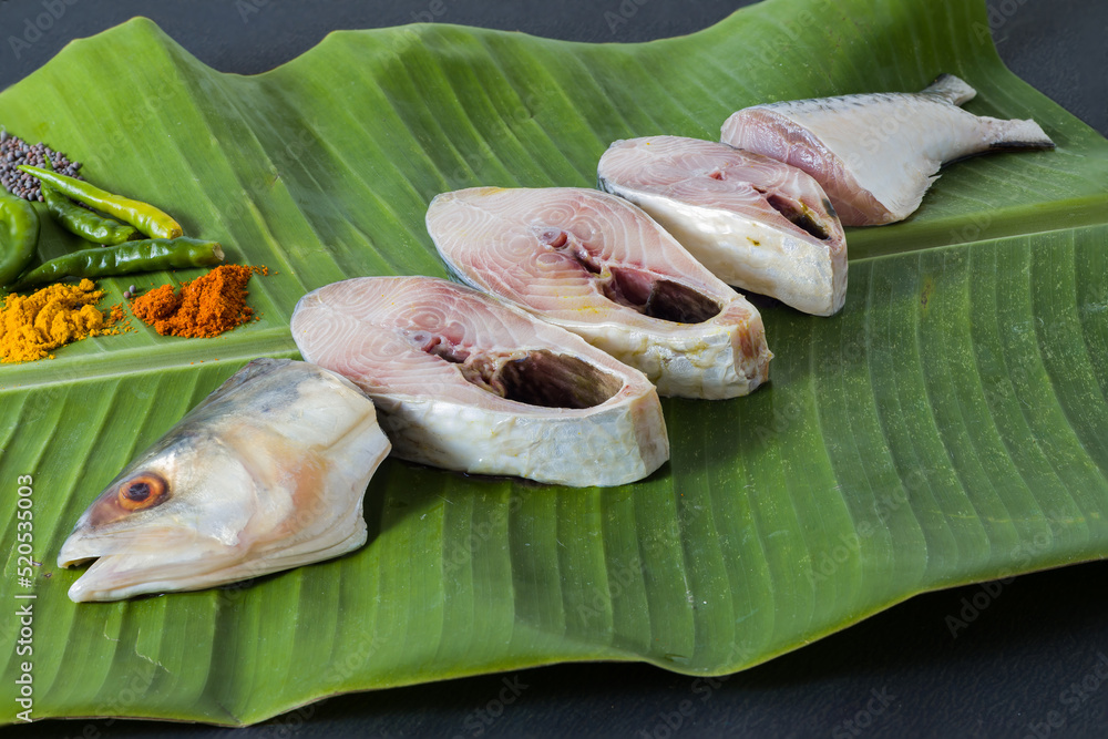 Raw hilsa fish cut into pieces kept on banana leaf for cooking. Shot ...