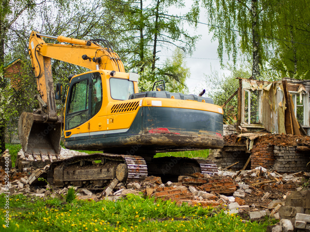 Demolition of a building by an industrial yellow excavator. Demolished ...
