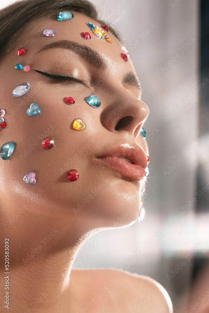Unusual makeup and face art with sparkling rhinestones on the skin. A ...